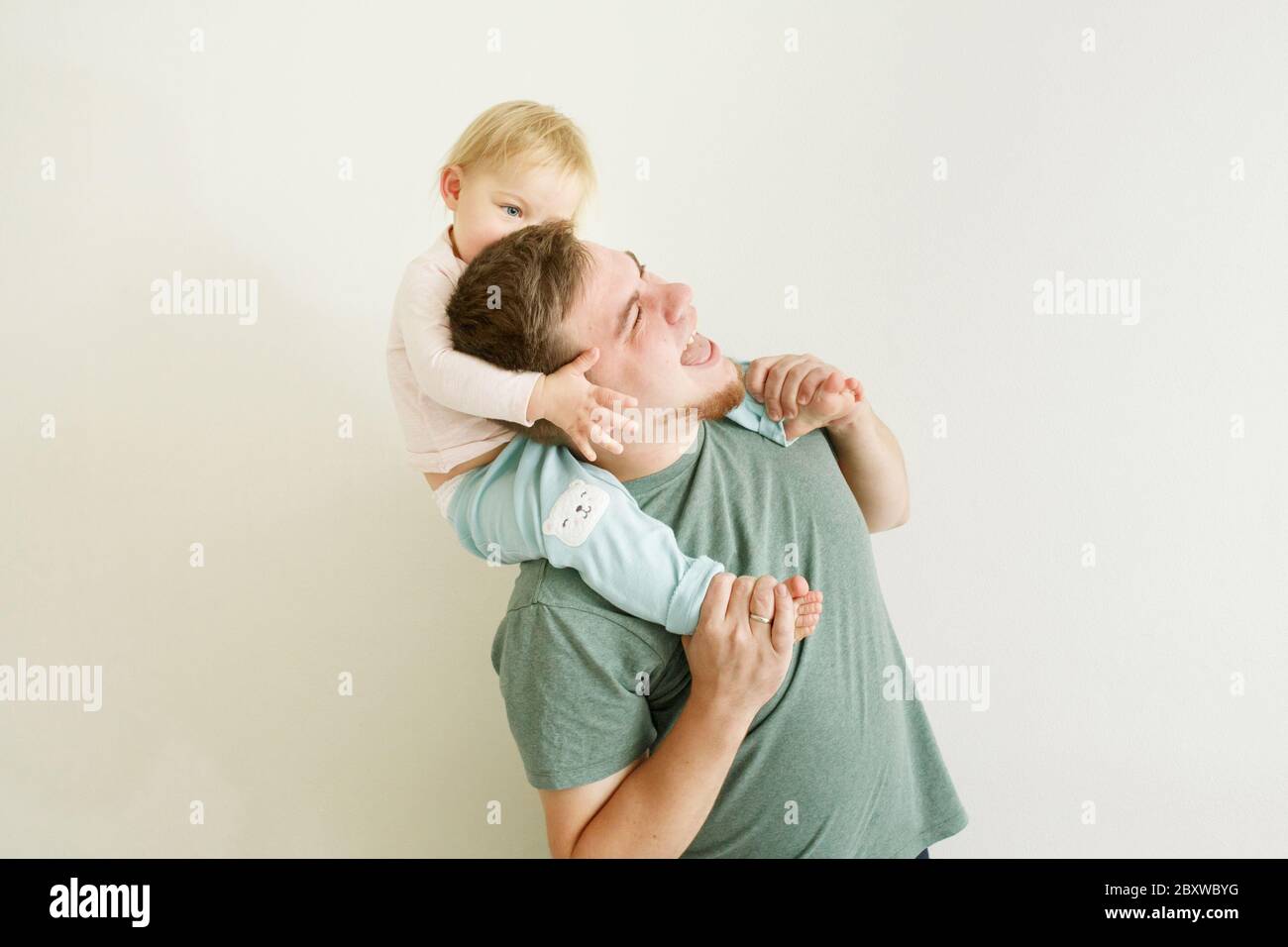 Young handsome father holding cute baby daughter kid on shoulders over ...