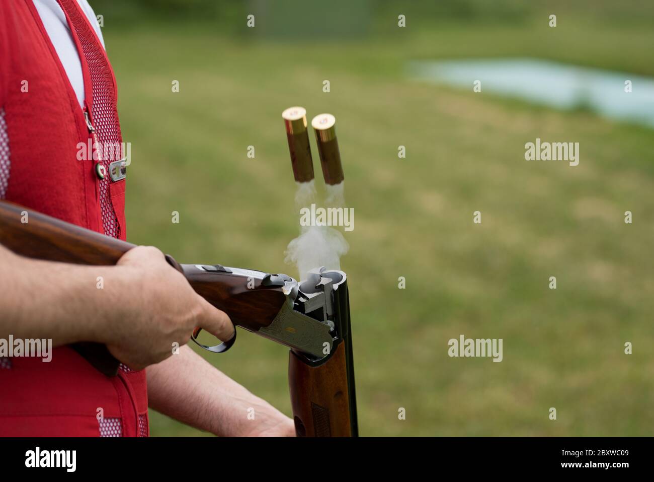 Rifle cartridges and smoke after firing. Man opens the shotgun bolt ...
