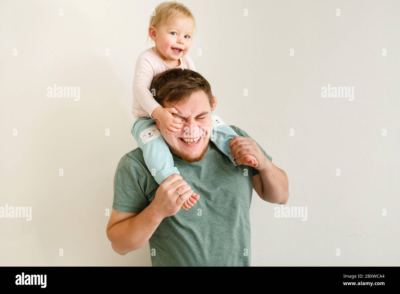 Loving handsome father holding cute baby daughter kid on shoulders over ...