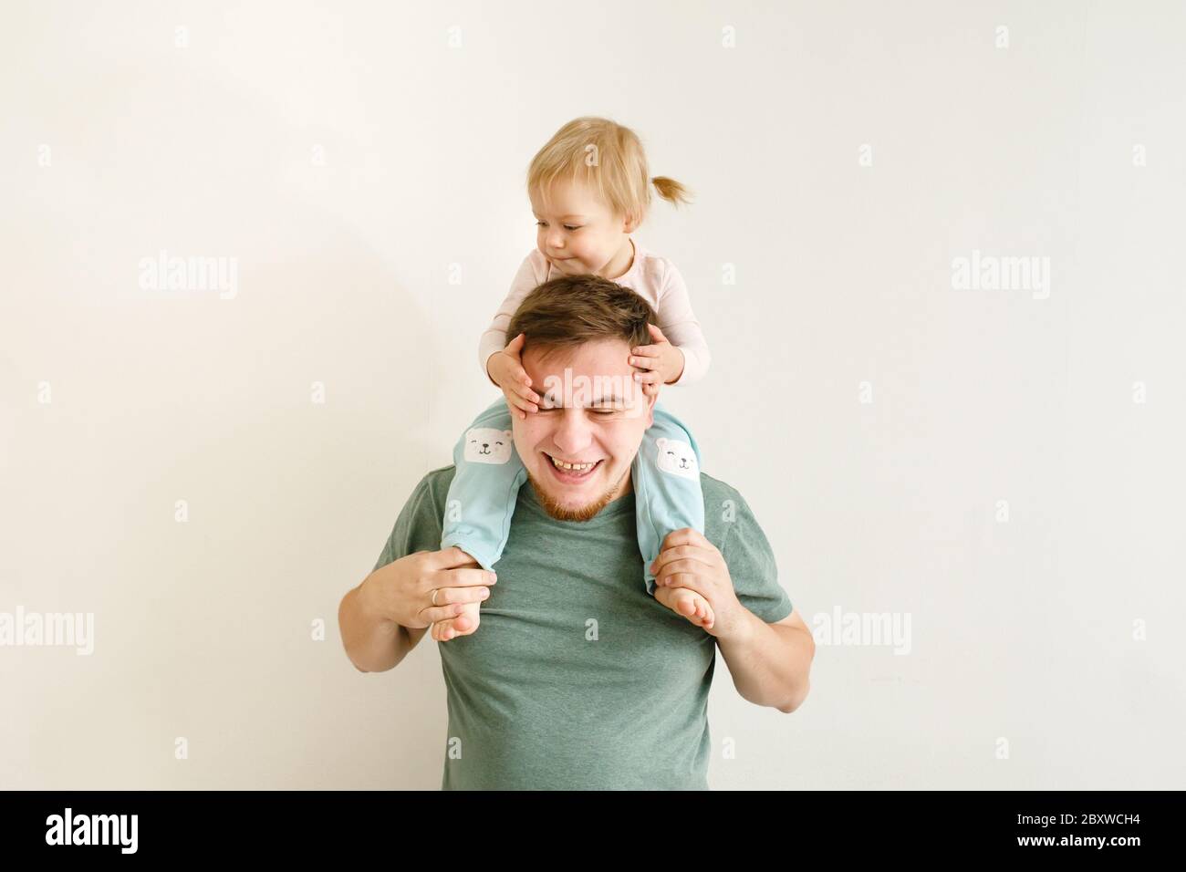 Young handsome father holding cute baby daughter kid on shoulders over ...