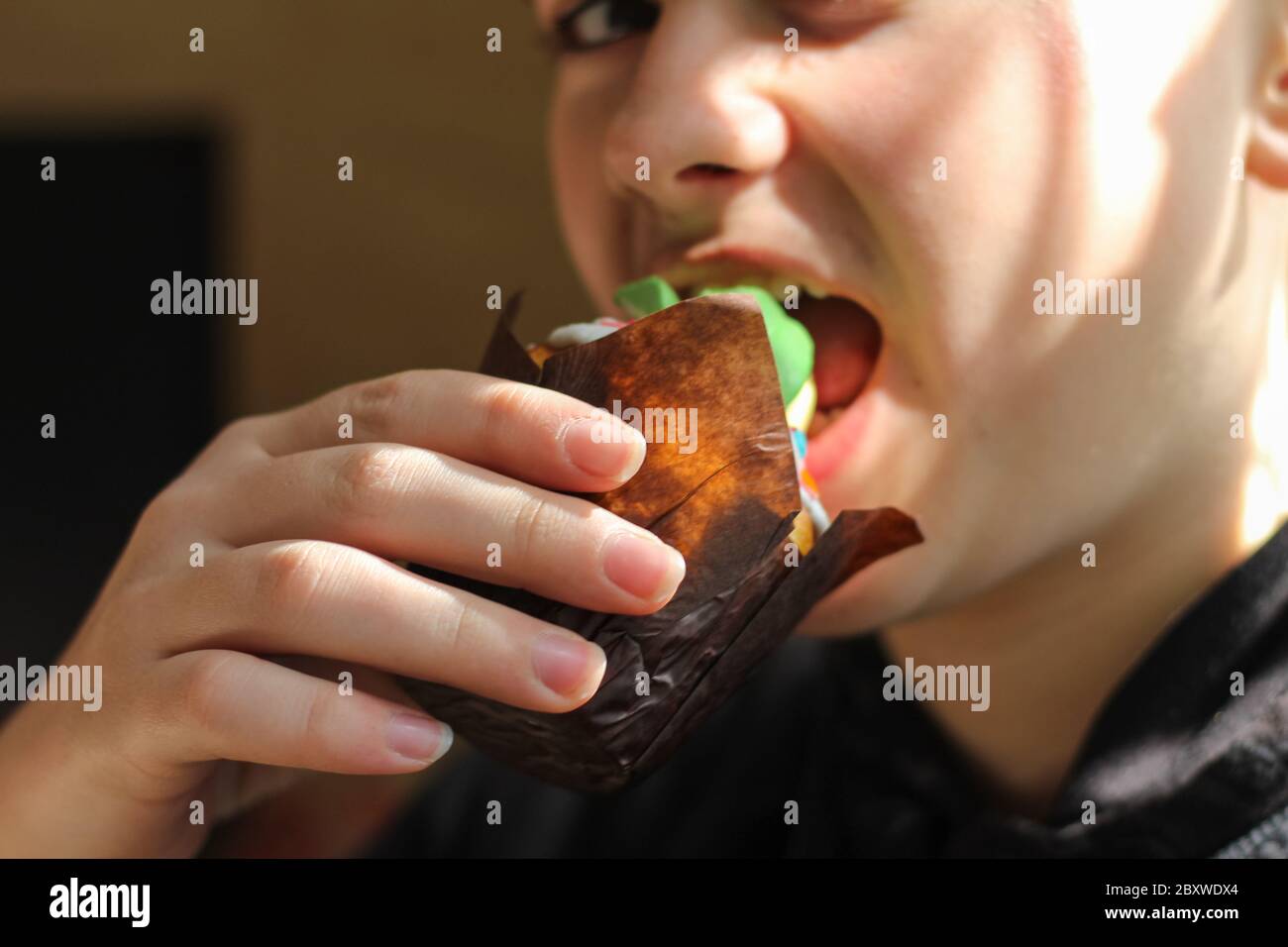White guy with bushy eyebrows eating a cupcake in brown paper Stock ...