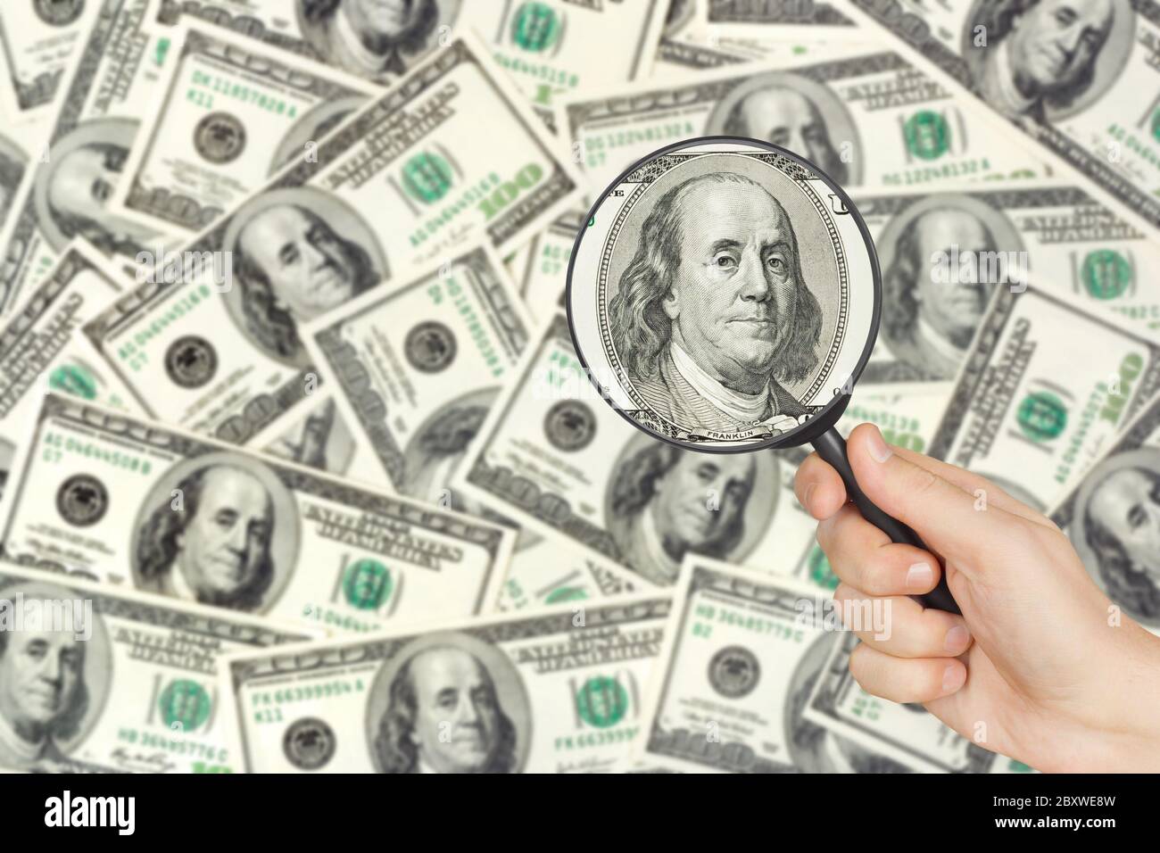Money and magnifying glass in hand Stock Photo - Alamy