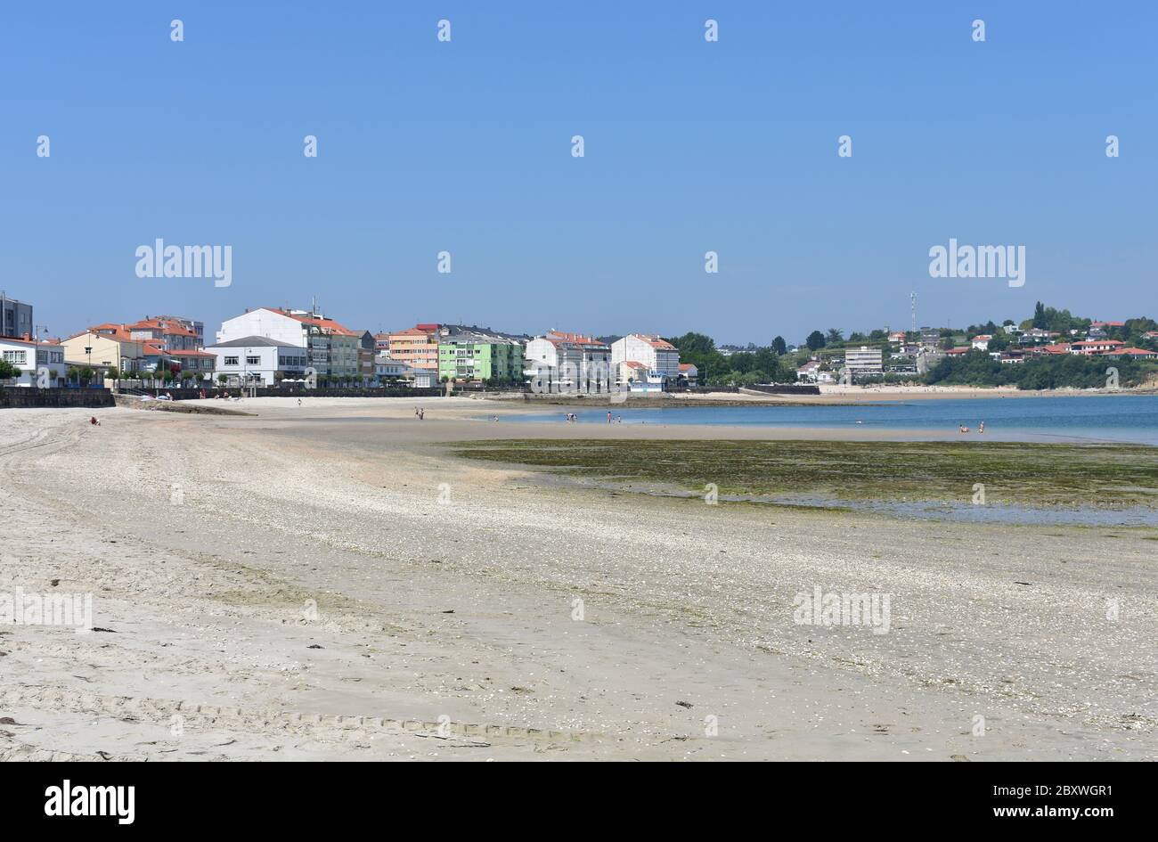 Coastal village with beach and people sunbathing with blue sky. Ares ...