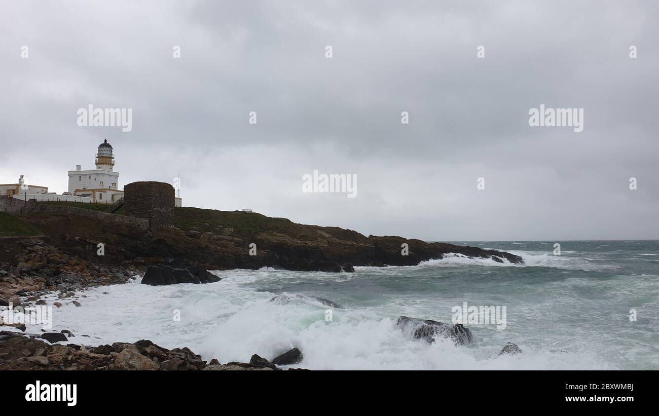 Lighthouse by rough sea Stock Photo - Alamy