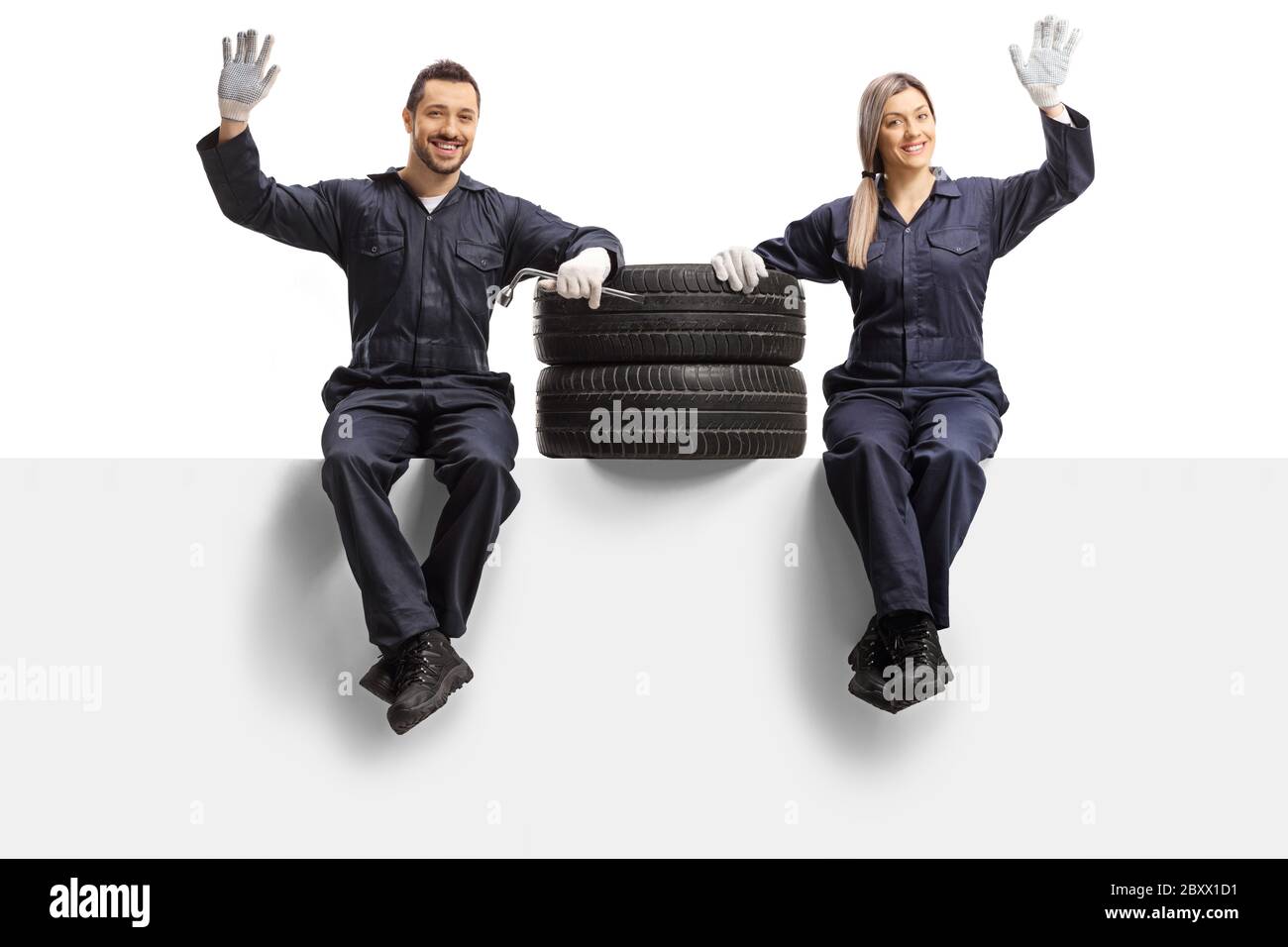 Male and female auto mechanic workers sitting on a panel with tires and ...