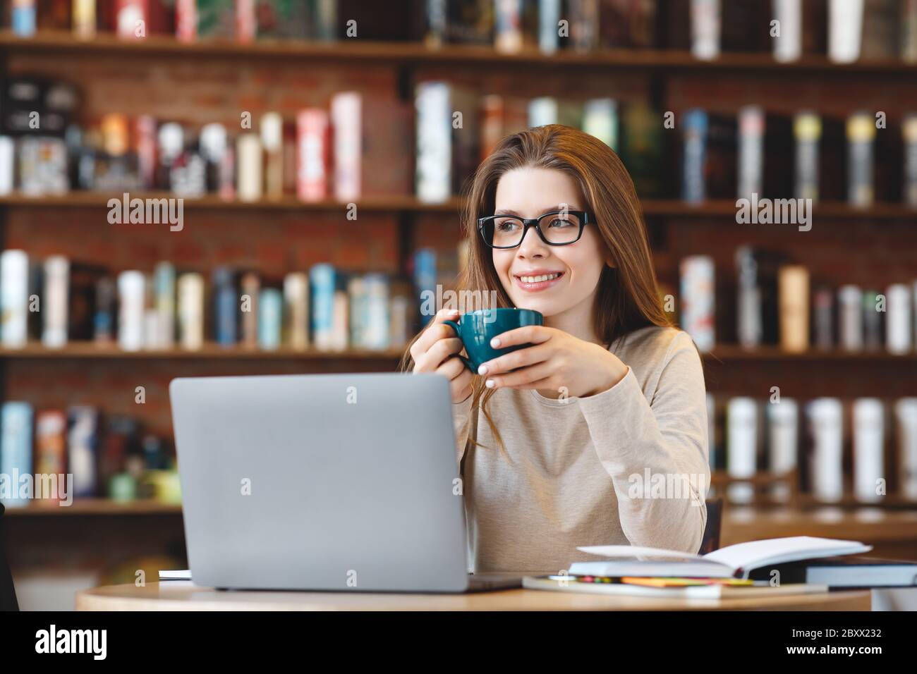 Happy young girl working on laptop computer, sitting in cafe Stock ...