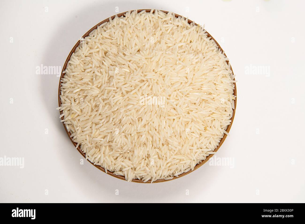 Uncooked dry rice in wooden bowl isolated on white Stock Photo - Alamy