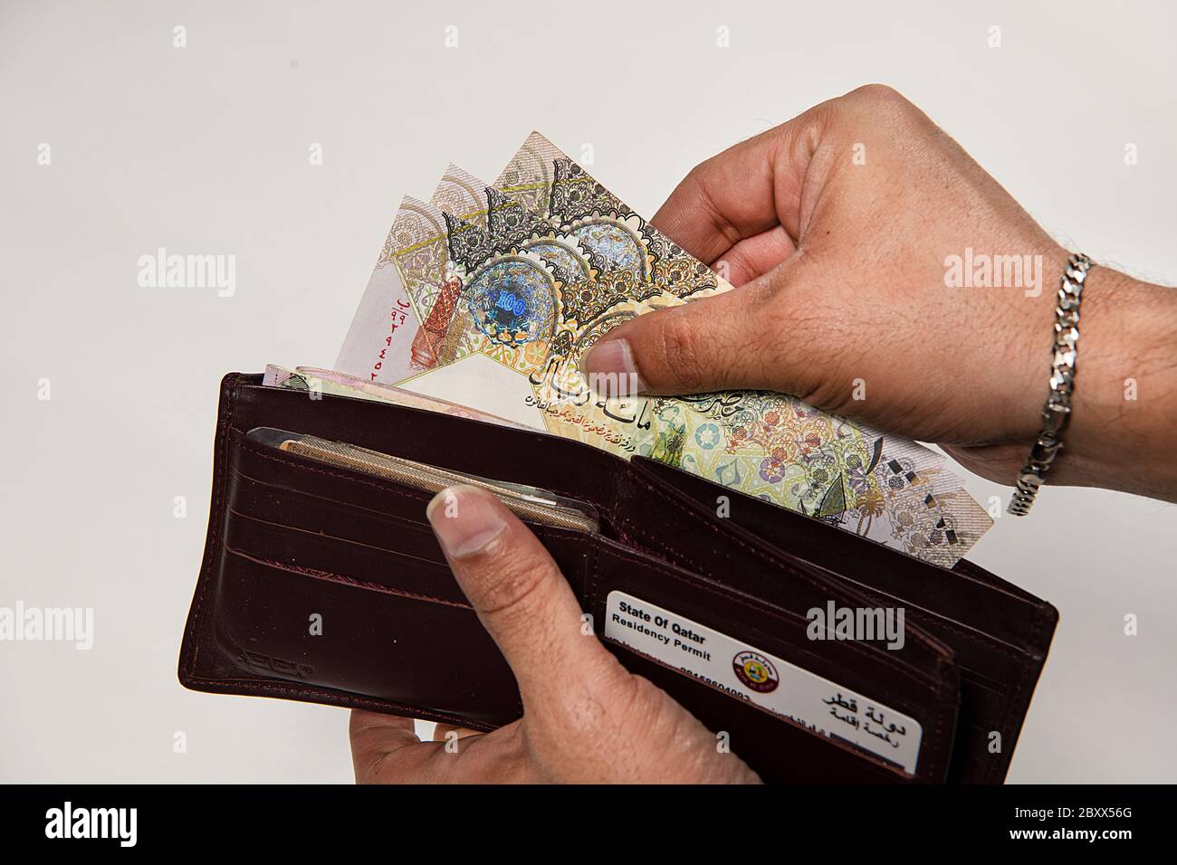 Men's hands holding wallet with Qatari notes. 100 Rial new notes ...