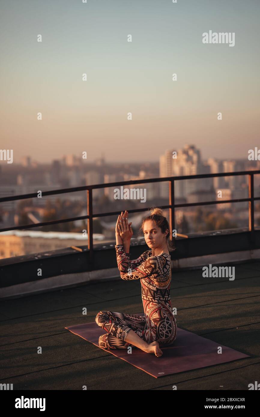 Woman doing yoga on the roof of a skyscraper in big city Stock Photo ...