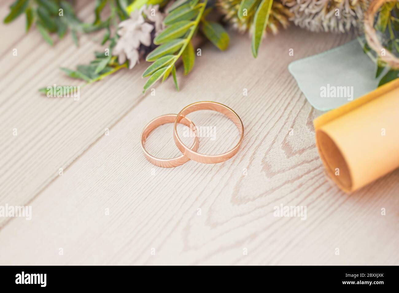 Close up view on wedding rings and two rolled paper sheets with wedding ...