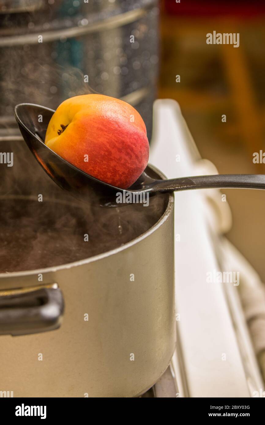 Slotted spoon being used to transfer a peach to ice cold water after ...