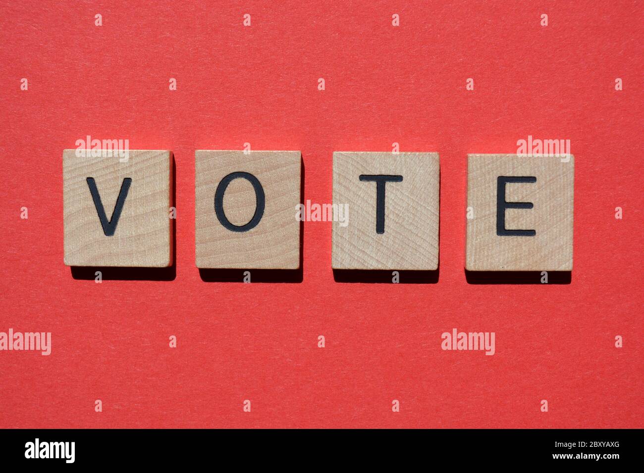 Vote, word in 3d wooden alphabet letters isolated on red background ...