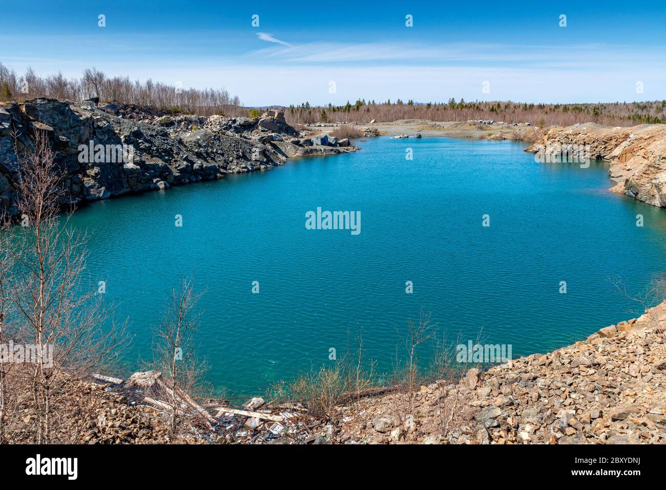 An old quarry filled with water, making it a pond. The water is bluish ...
