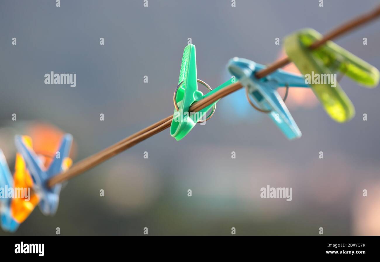 Colorful clothes pegs hanging in wire Stock Photo - Alamy