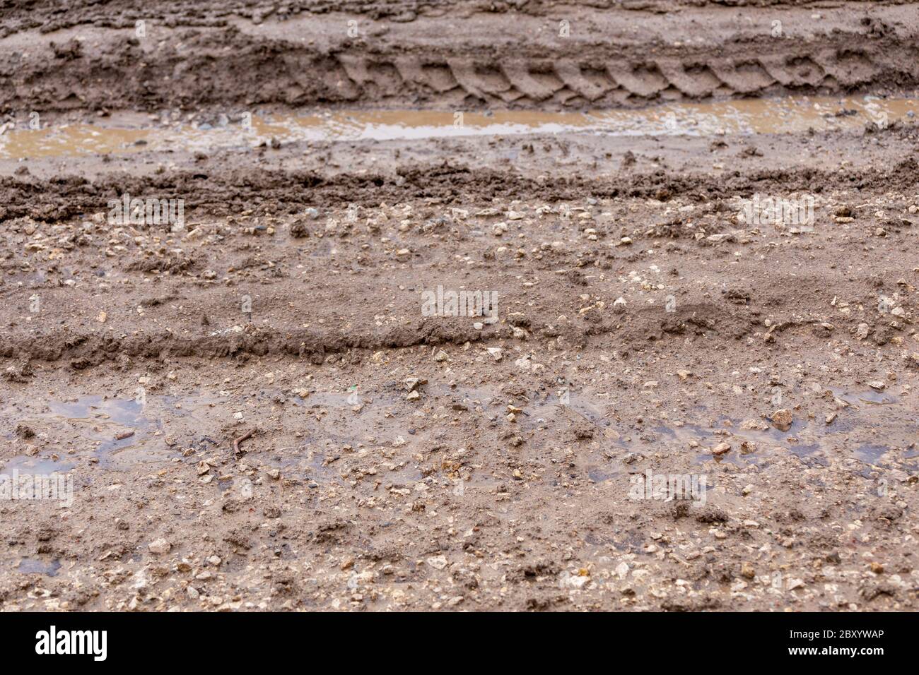 dirty clay mud road with puddles and tire tracks - closeup with ...