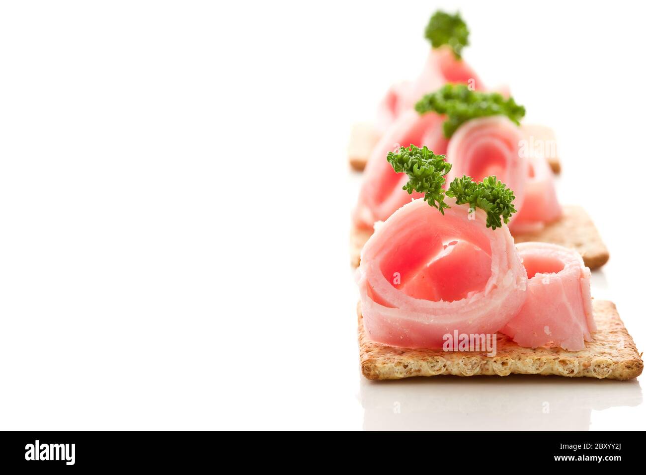Crackers canapes with ham and parsley Stock Photo - Alamy