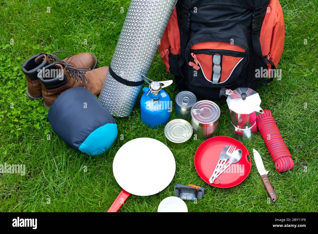 Picture of camping tools on the grass - backpack, tent, gas tank, cans ...