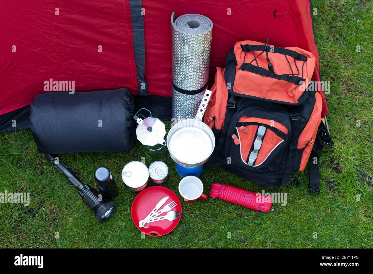 Picture of camping tools on the grass - backpack, tent, gas tank, cans ...