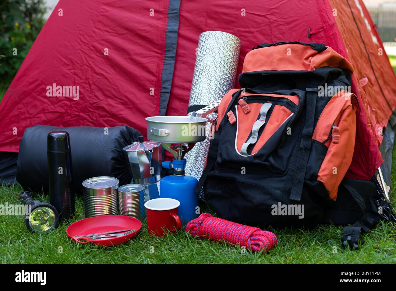 Picture of camping tools on the grass - backpack, tent, gas tank, cans ...