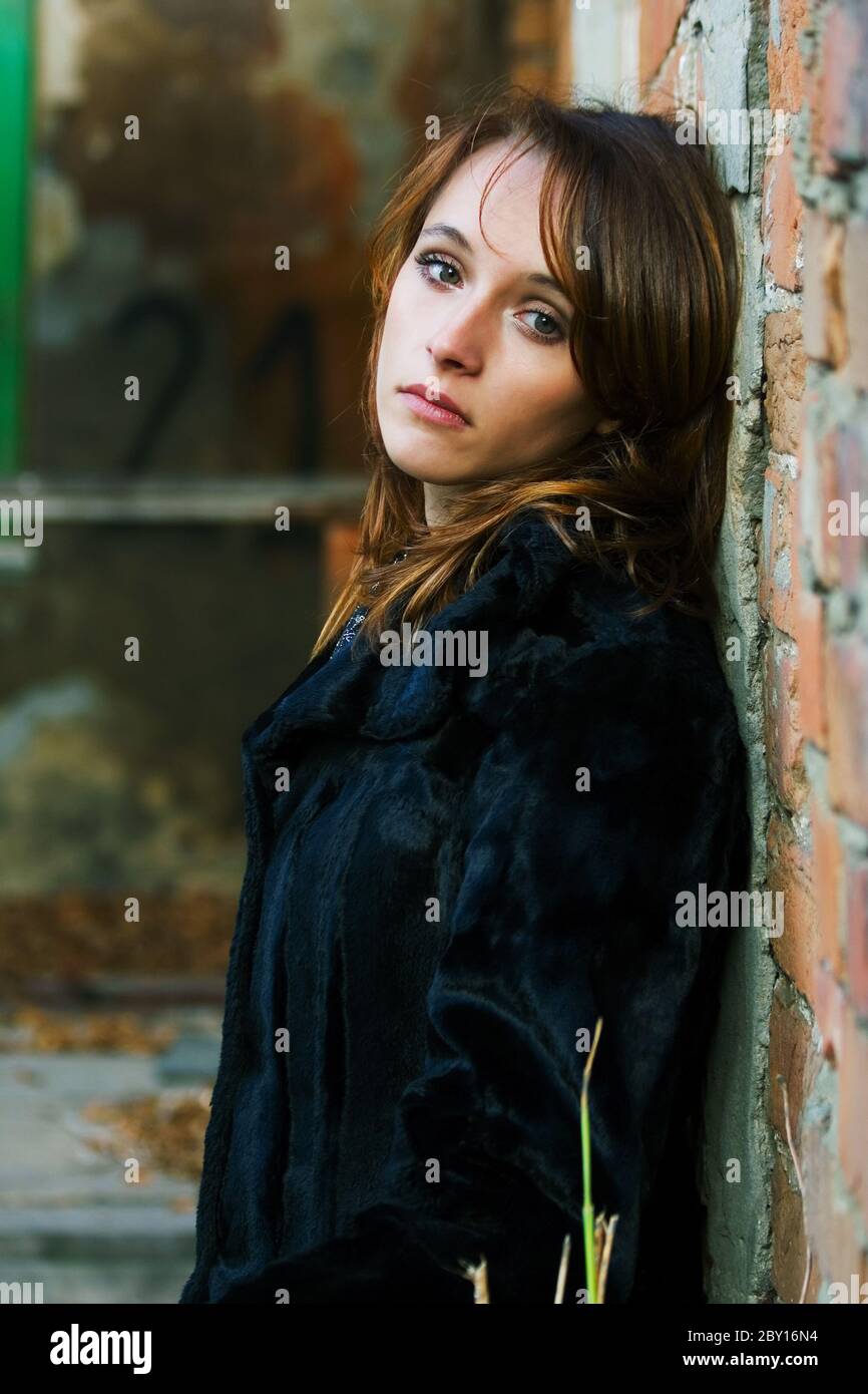 Sad woman against a stone wall Stock Photo - Alamy