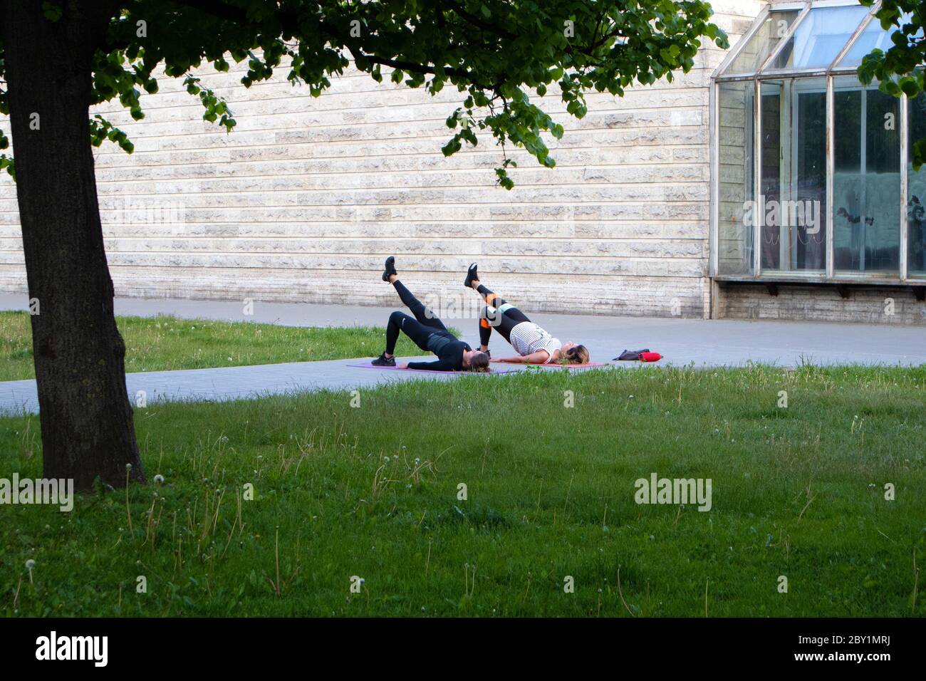 Two young active women doing gymnastics outdoors near the lawn with ...