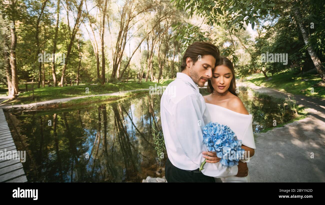 Wedding Couple Embracing Standing Near Lake In Park Panorama Stock