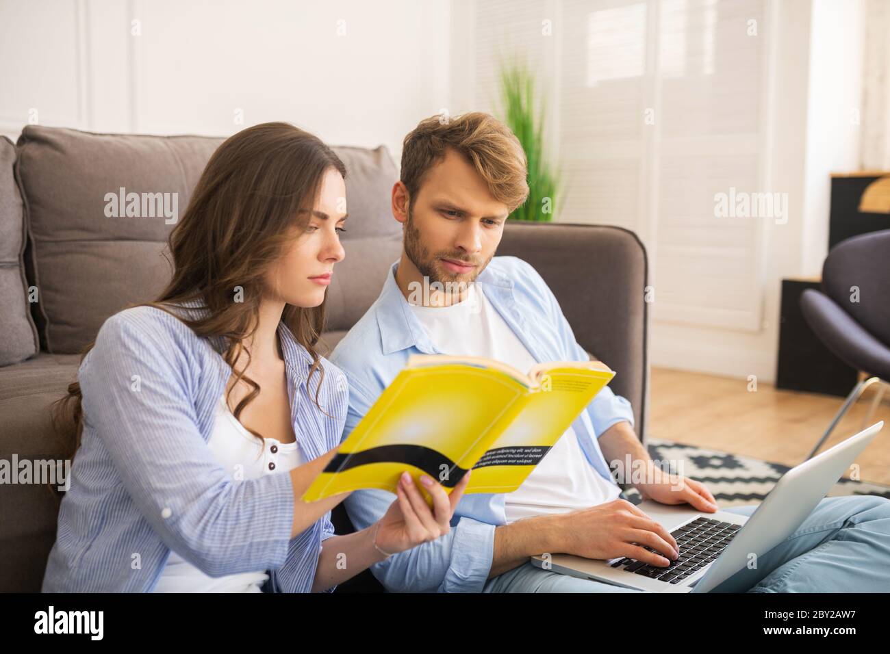 Young couple looking interested, woman showing something in a book ...