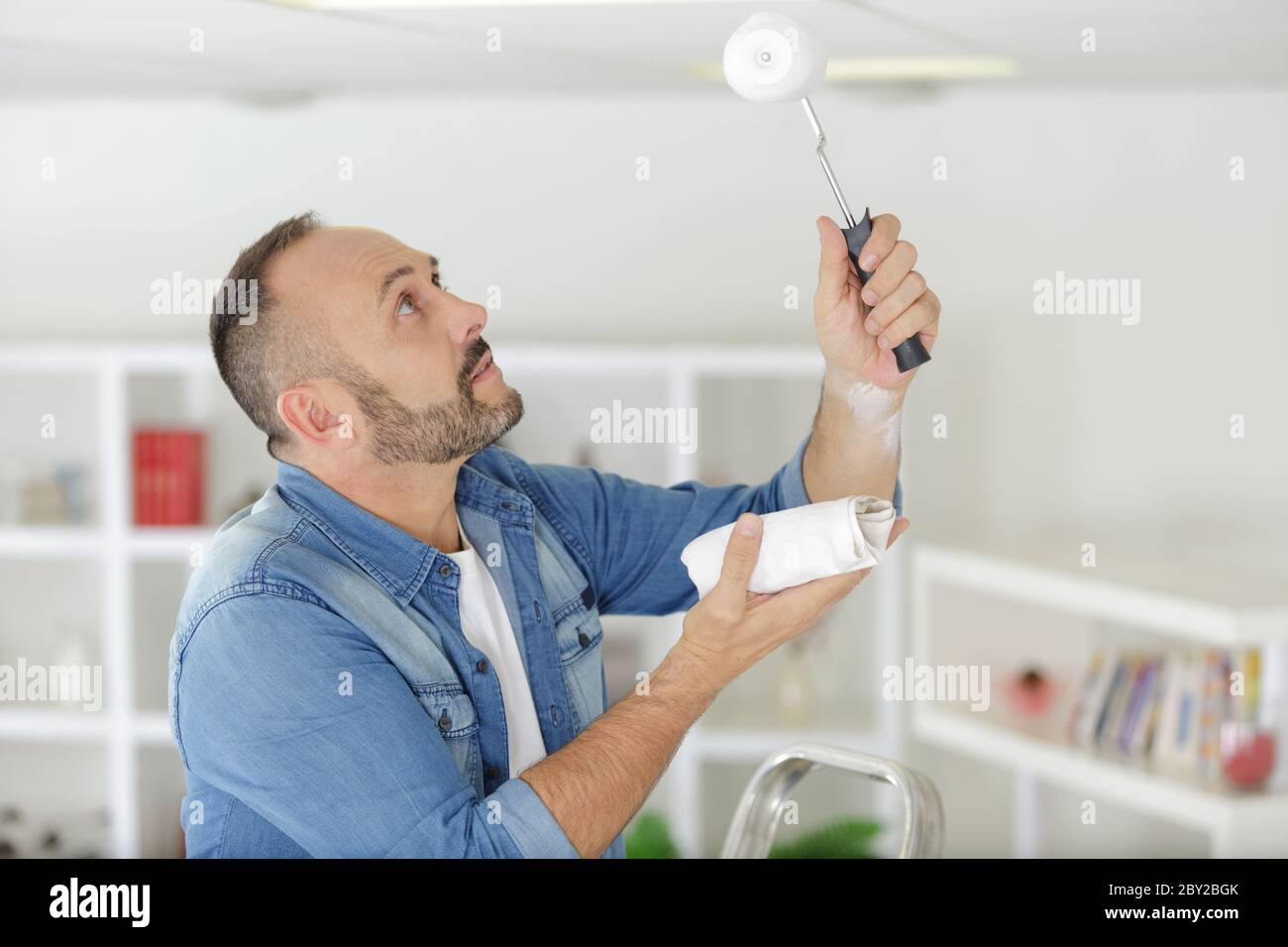 man painting ceiling in a new house Stock Photo - Alamy