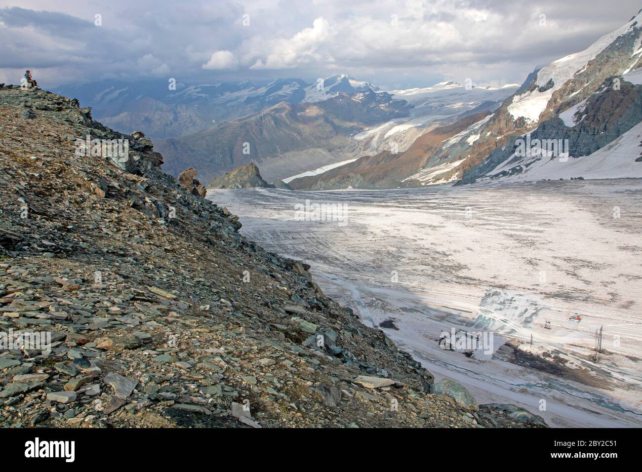 Hiker sitting above a glacier at Rifugio Teodulo Stock Photo - Alamy