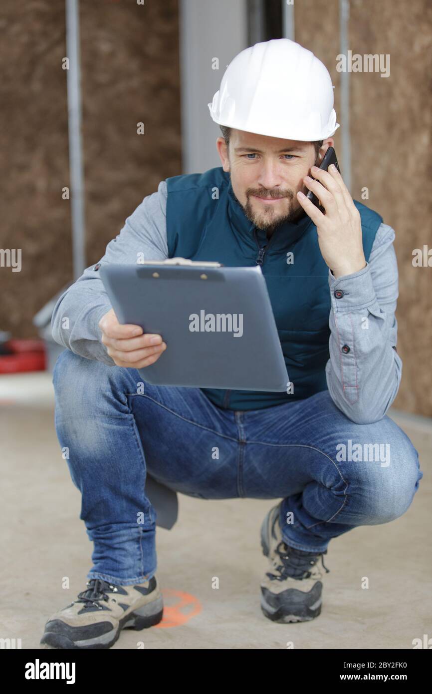 young handyman holding clipboard in his hand and making call Stock ...