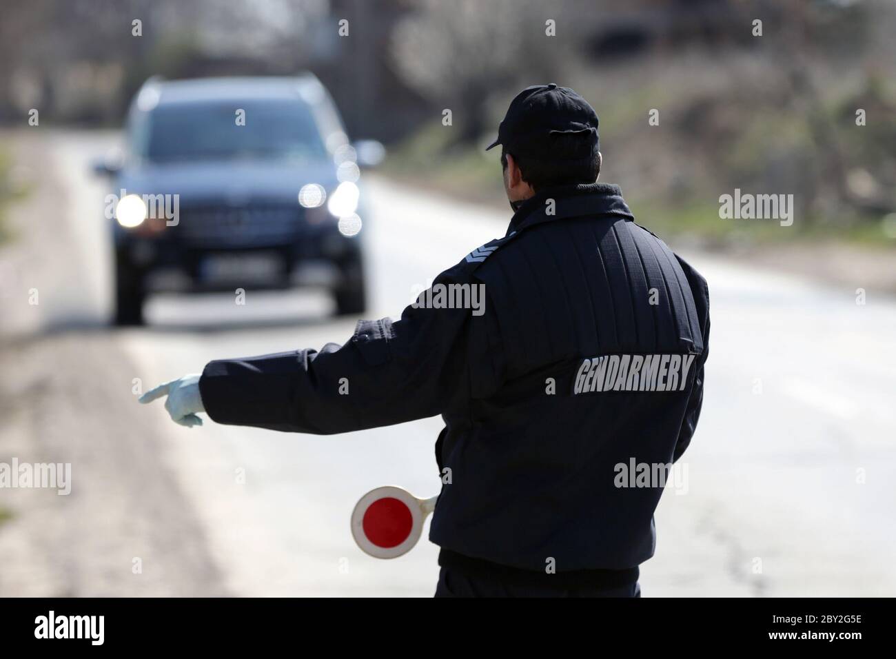 A police officer in a gendarmery uniform stops a car for a road check ...