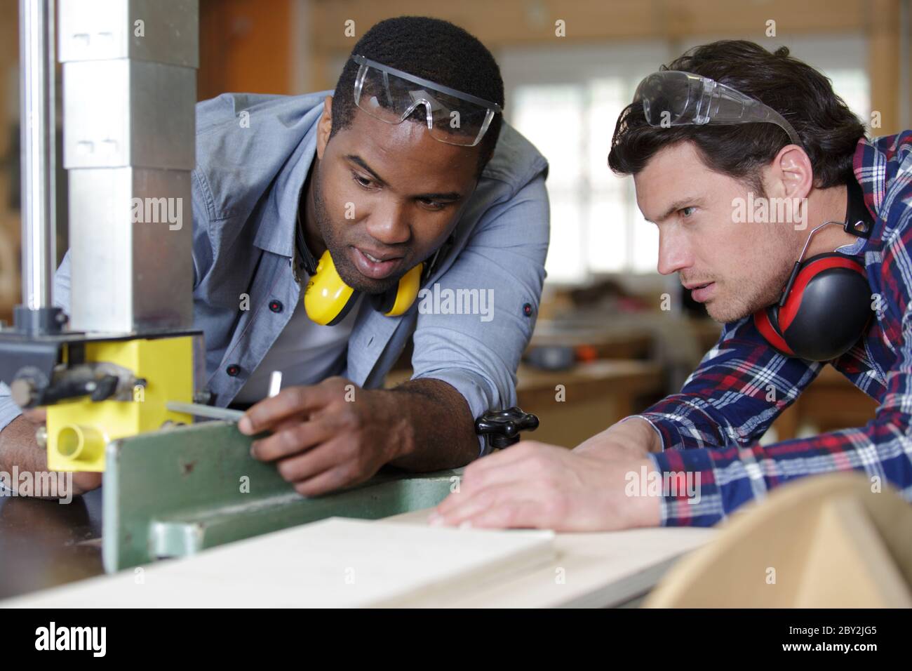 two men holding timber on woodworking machine Stock Photo - Alamy