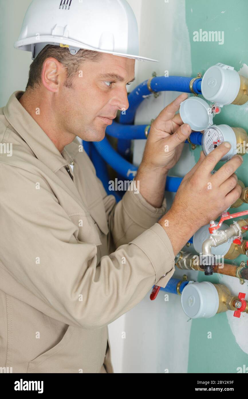 male plumber fixing water meter with adjustable wrench Stock Photo - Alamy
