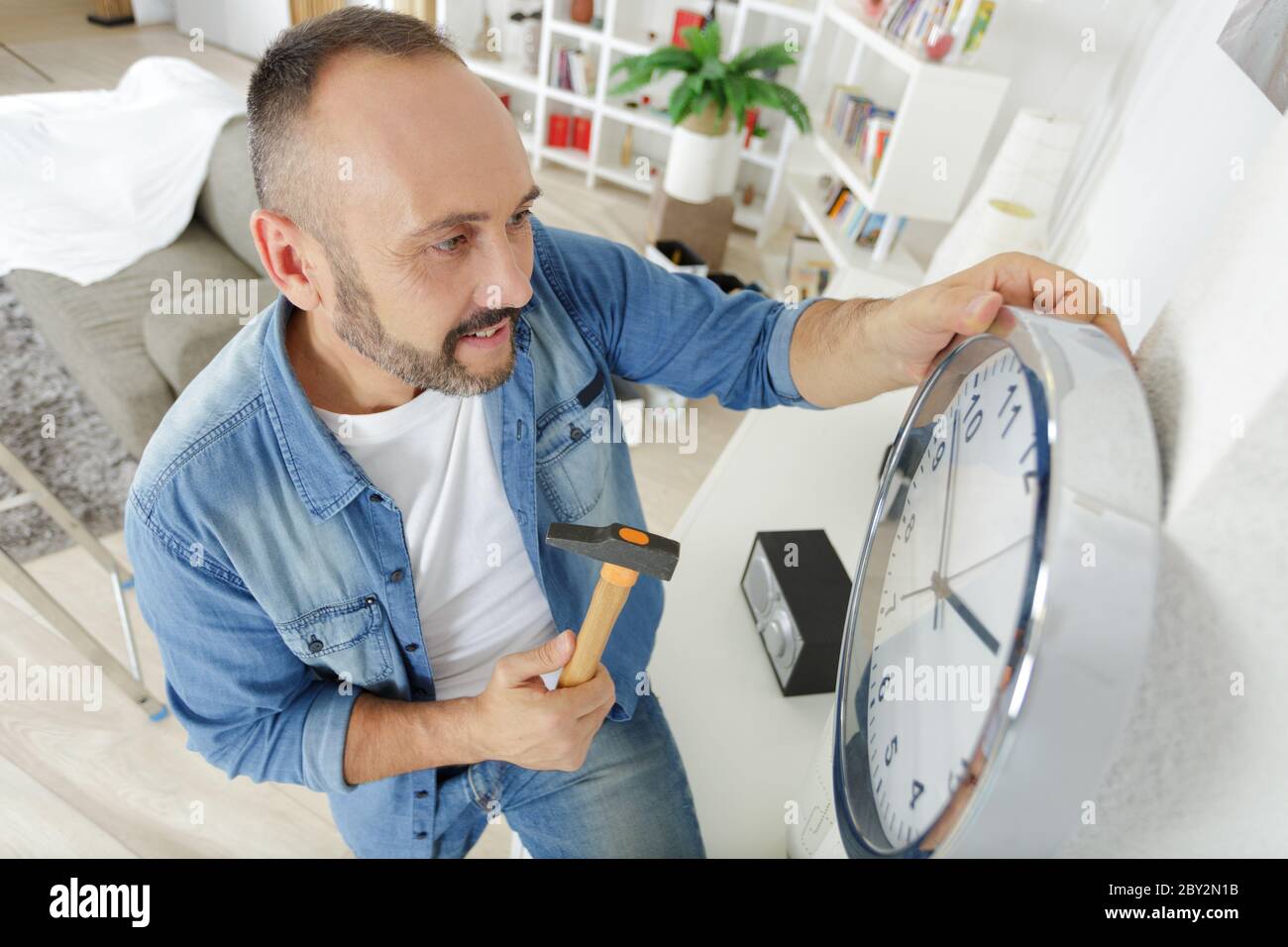 man hanging a clock on the wall in his house Stock Photo - Alamy