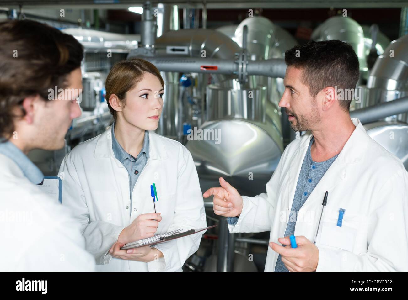 worker giving tour of factory premises vats in background Stock Photo ...