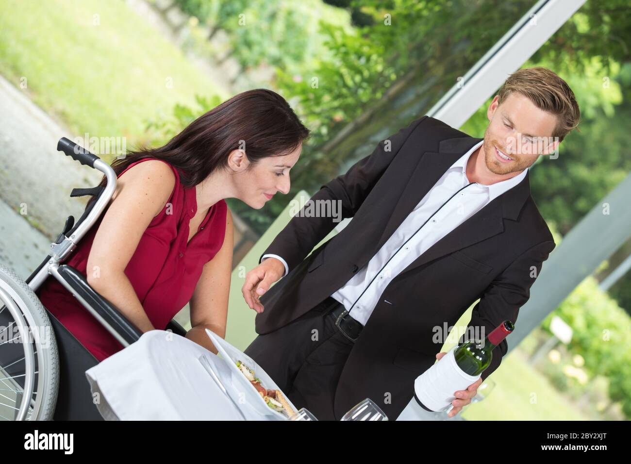 young waiter serving wine to disabled woman at the restaurant Stock ...