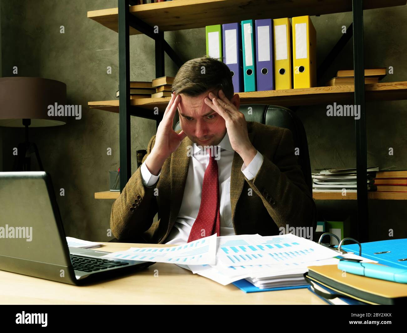 A frustrated, tired businessman reads a statement of financial loss ...