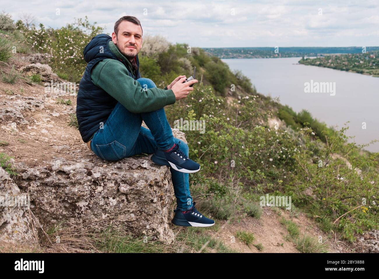 Young man piloting drone outdoor in nature. Guy testing aerial unmanned ...