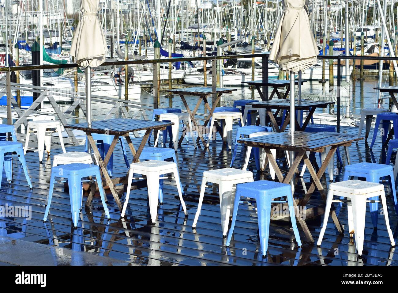 Outdoor plastic chairs and wooden tables on open deck in marina with ...