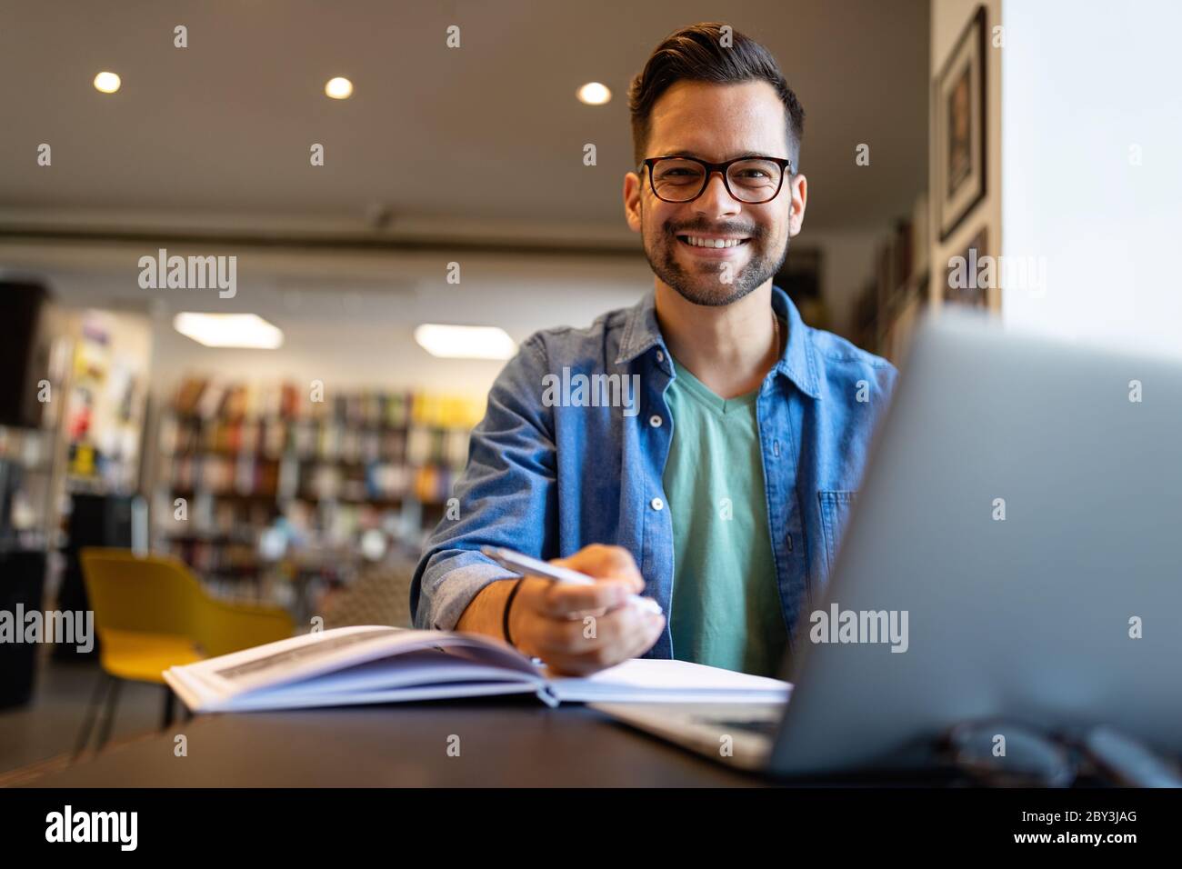 Smiling male student working and studying in a library Stock Photo - Alamy
