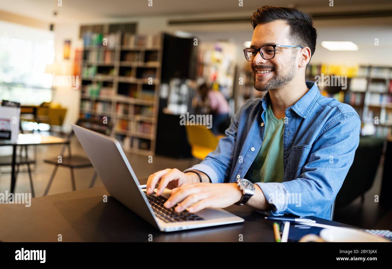 Smiling male student working and studying in a library Stock Photo - Alamy