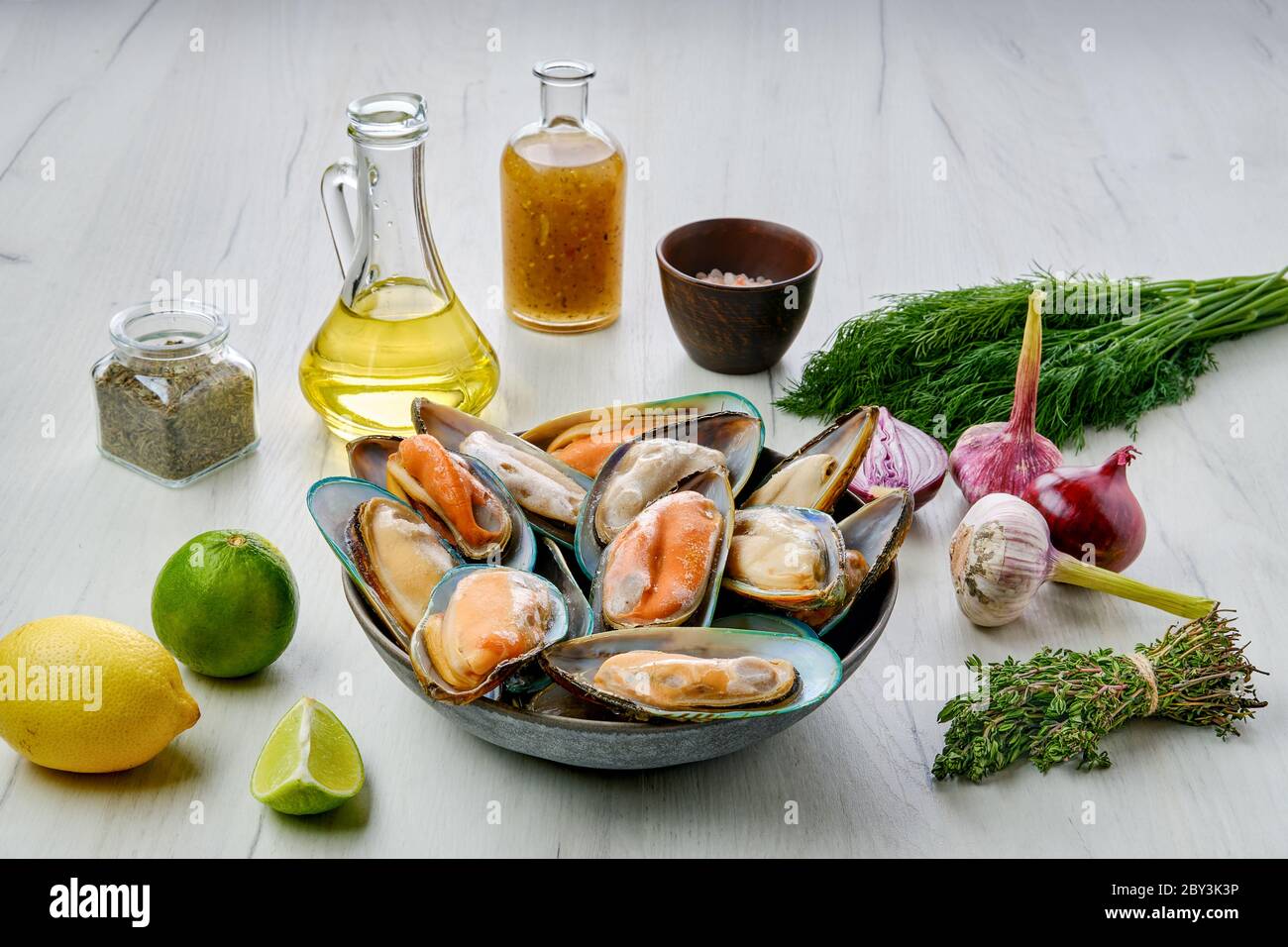 Plate with raw large mussels in half shell with spice on wooden table ...
