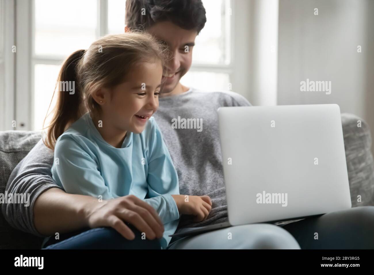 Happy dad and small daughter use laptop together Stock Photo - Alamy