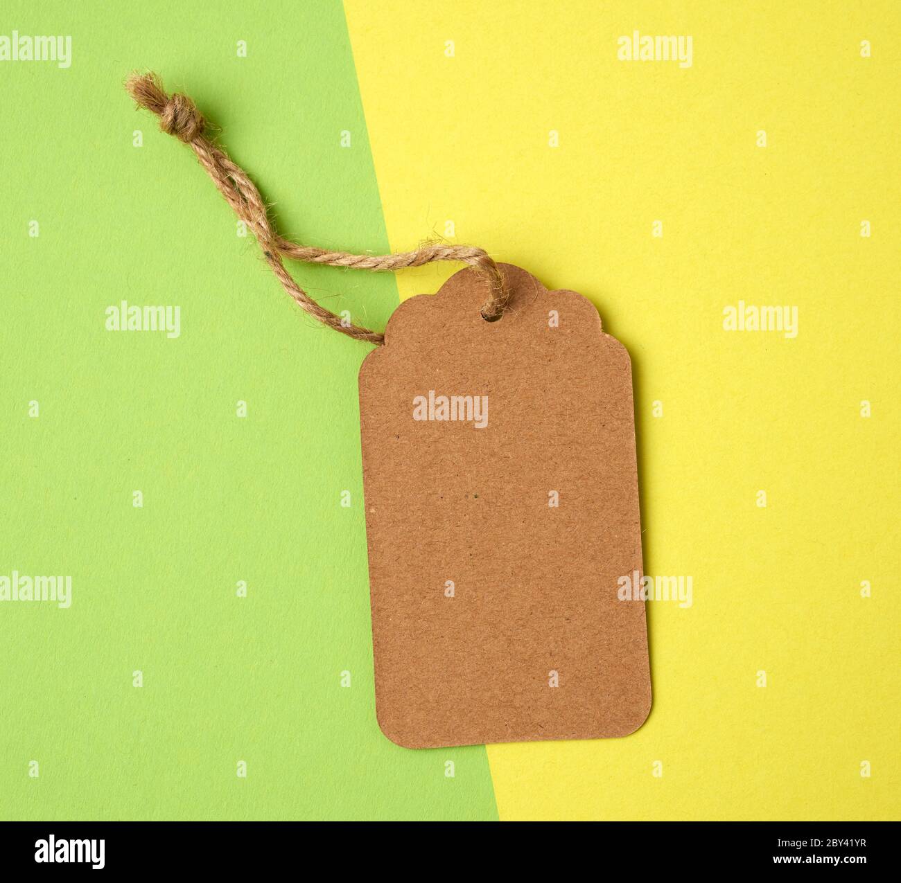 empty paper brown rectangular price tag on a rope on a colored bright ...