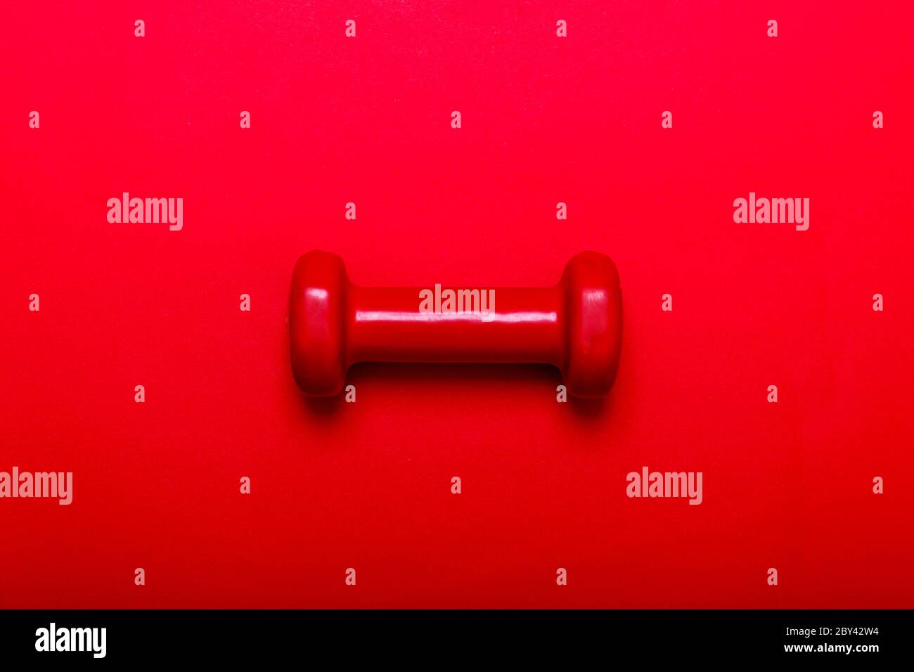 Red dumbbell for fitness isolated on dark red background Stock Photo ...