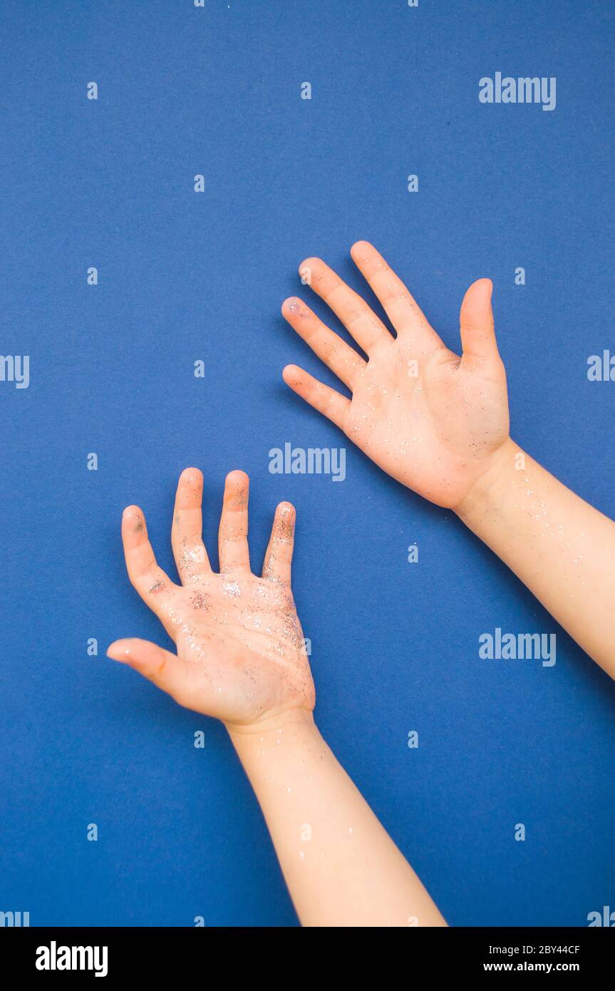 Child's hands with blue and silver color glitter and confetti on ...