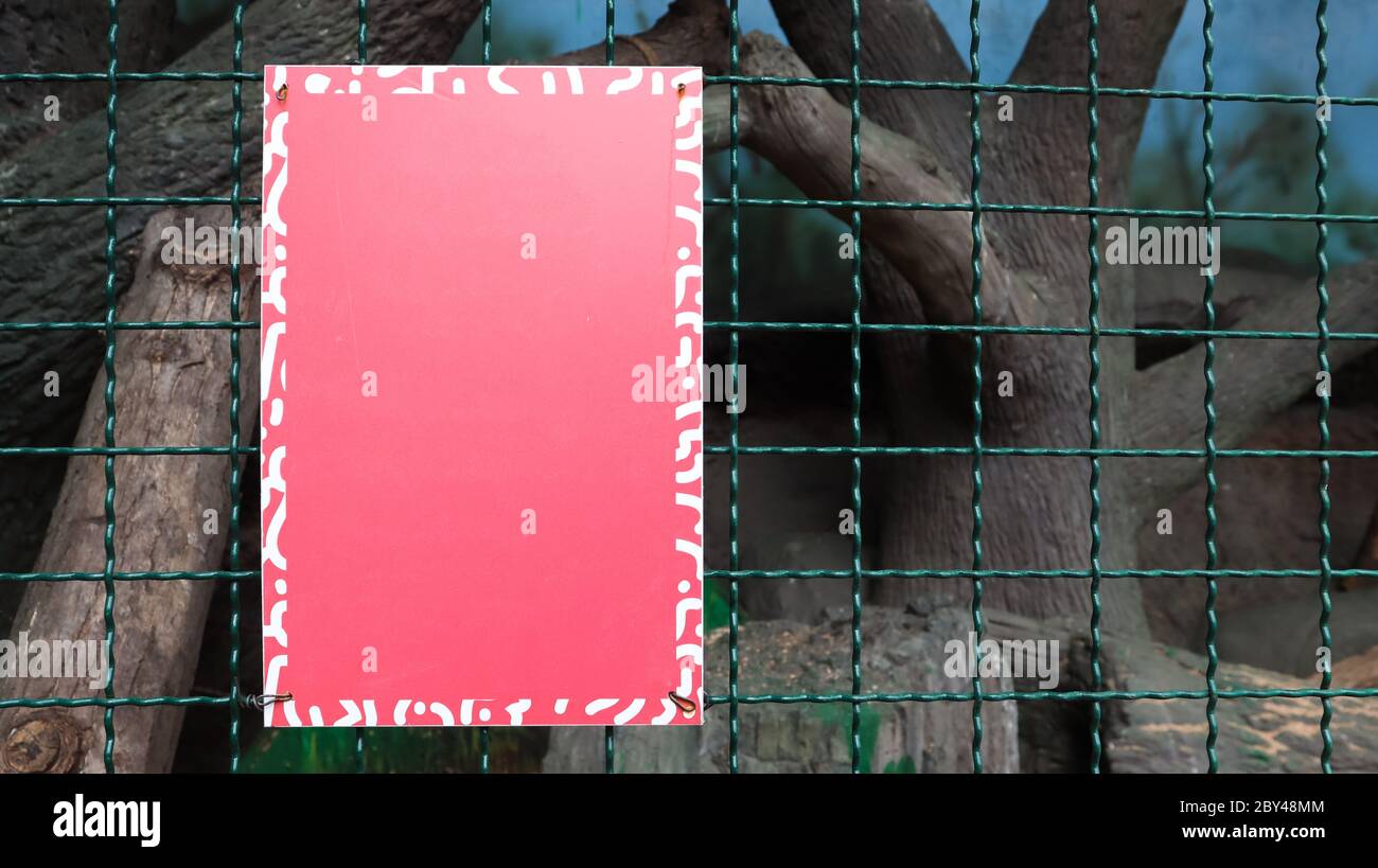 Red blank metallic signboard on a fence for artwork template design ...