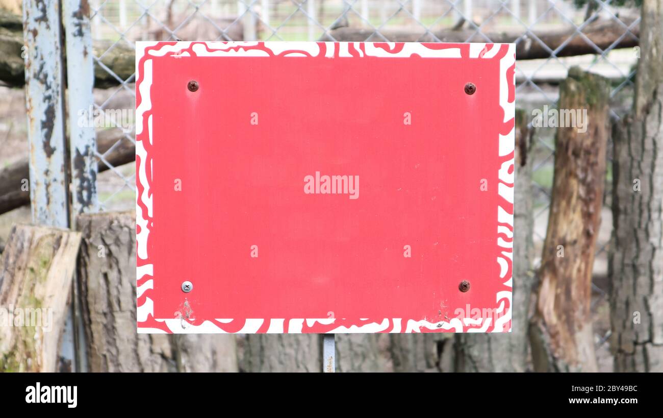 Red blank metallic signboard on a fence for artwork template design ...