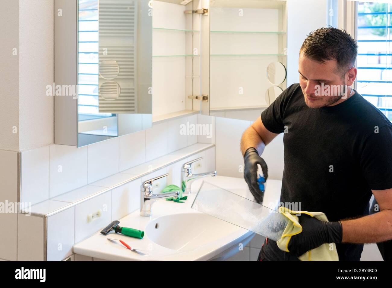 A professonal cleaner cleaning a bathroom and the glass shelves in the ...