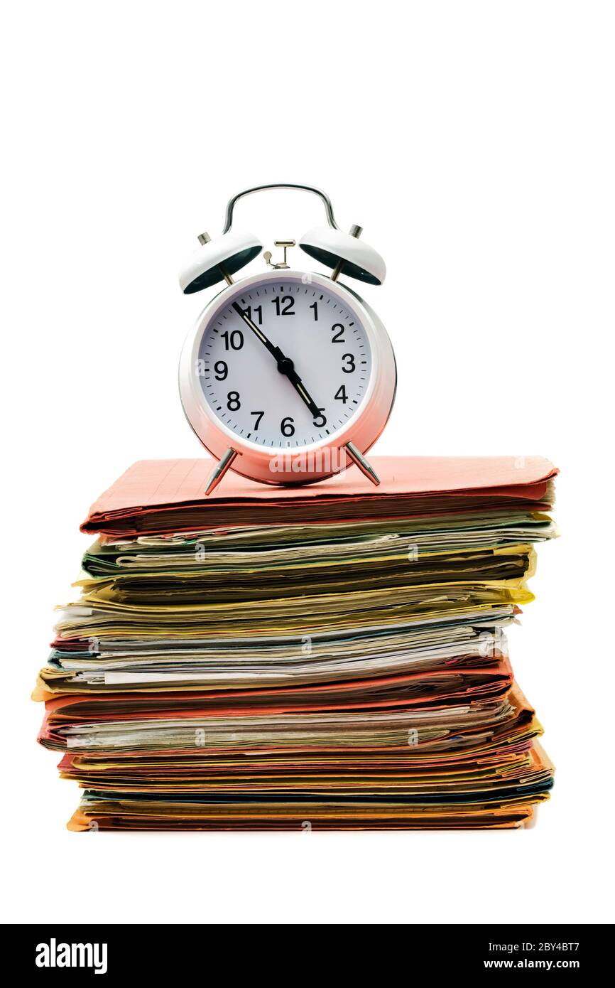 stack of file folders with alarm clock on top showing 5 minutes to five ...